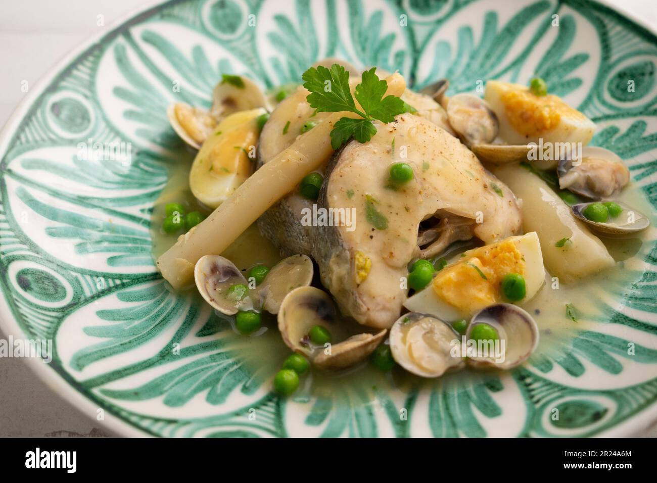 Basque-style hake cooked with green parsley and garlic sauce, served ...