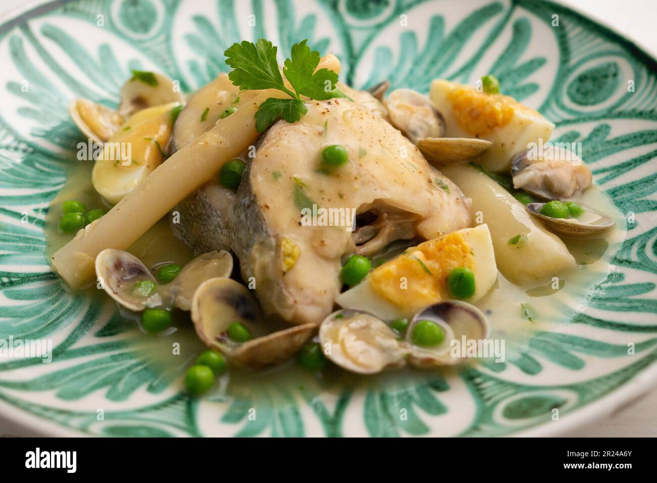 Basque-style hake cooked with green parsley and garlic sauce, served ...