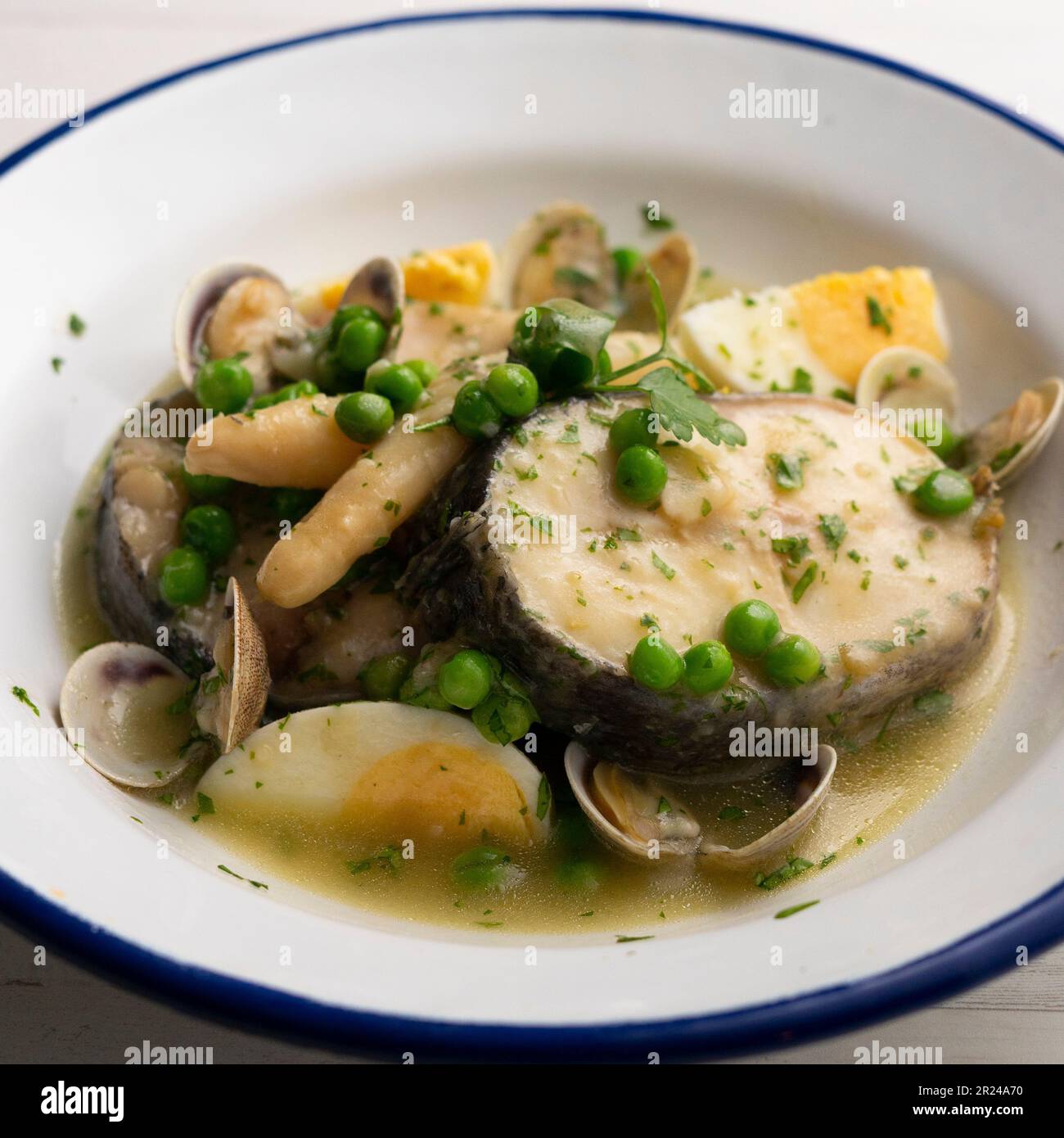 Basque-style hake cooked with green parsley and garlic sauce, served ...