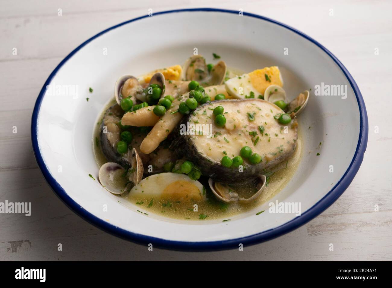 Basque-style hake cooked with green parsley and garlic sauce, served ...