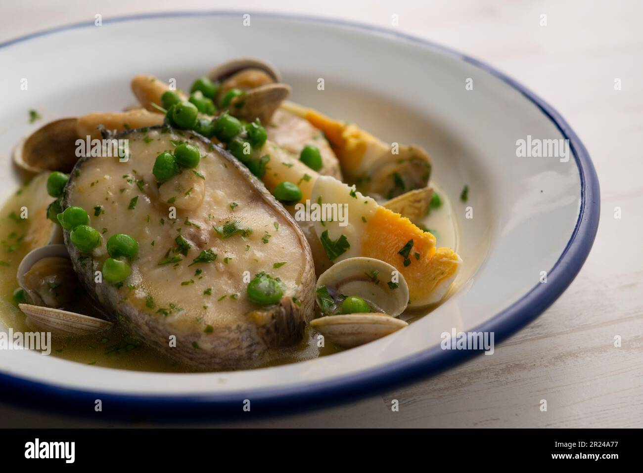 Basque-style hake cooked with green parsley and garlic sauce, served ...