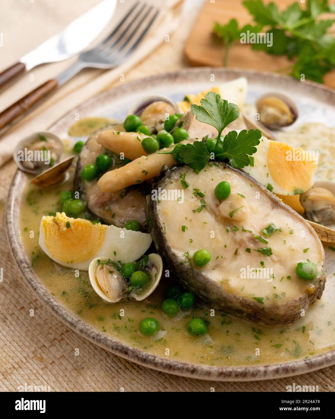 Basque-style hake cooked with green parsley and garlic sauce, served ...