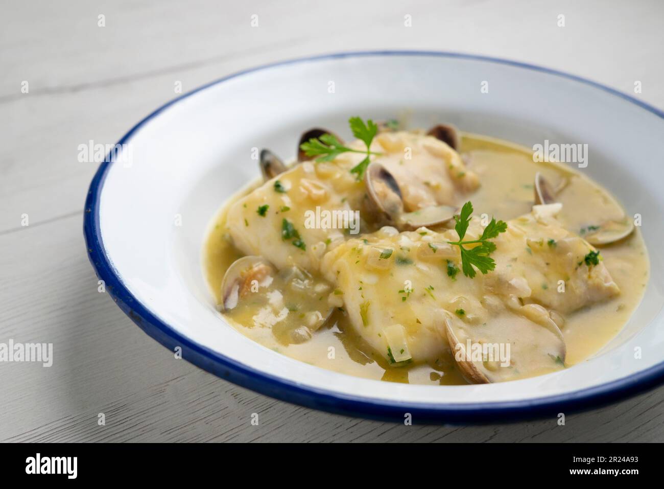 Basque-style hake cooked with green parsley and garlic sauce, served ...
