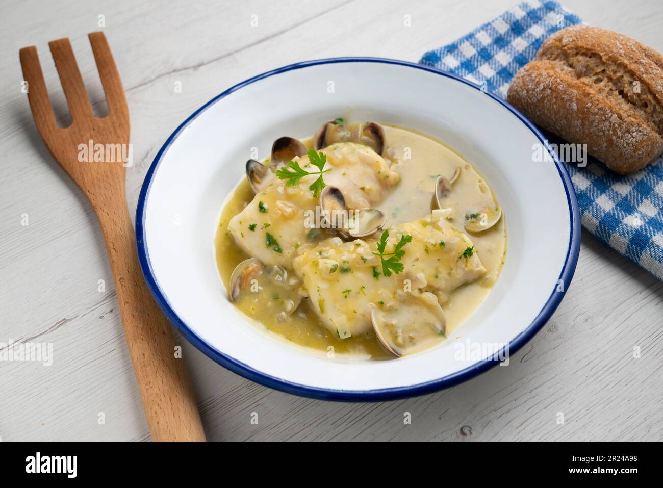 Basque-style hake cooked with green parsley and garlic sauce, served ...