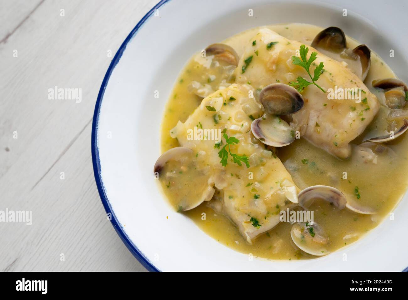 Basque-style hake cooked with green parsley and garlic sauce, served ...