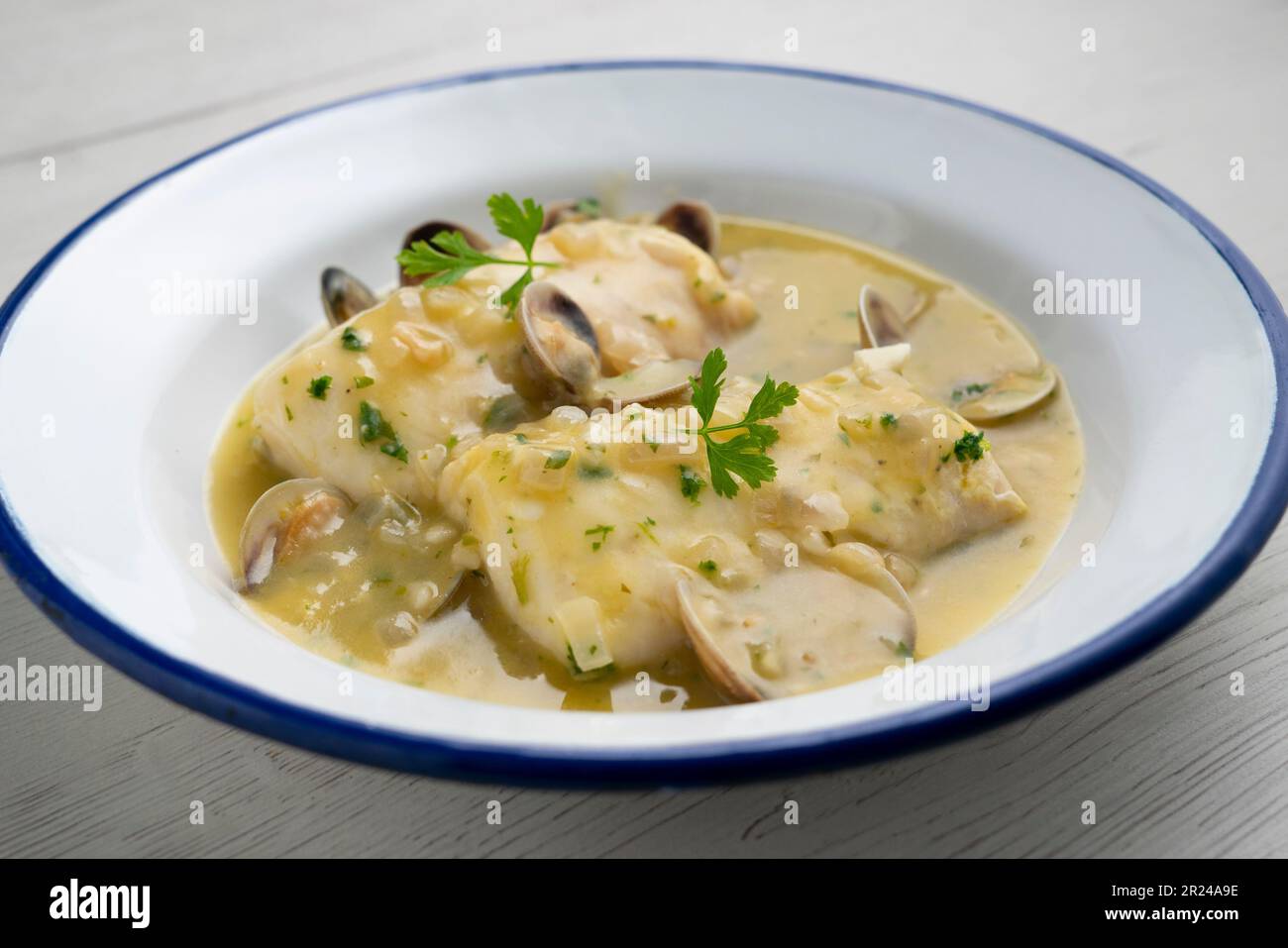 Basque-style hake cooked with green parsley and garlic sauce, served ...