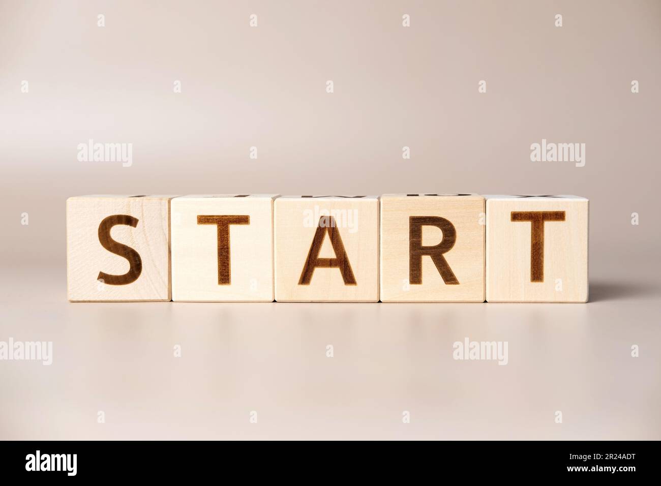 The word START on wooden cubes on a beige neutral studio background ...