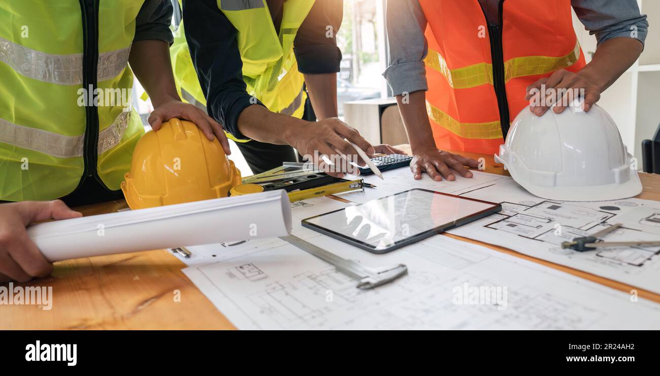 construction engineers team using blueprint and tablet of project plan ...