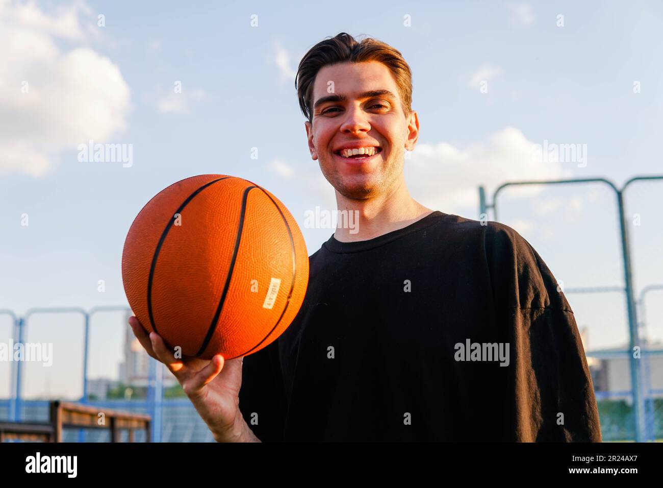 Young brunette man holding basketball ball looking positive and happy ...