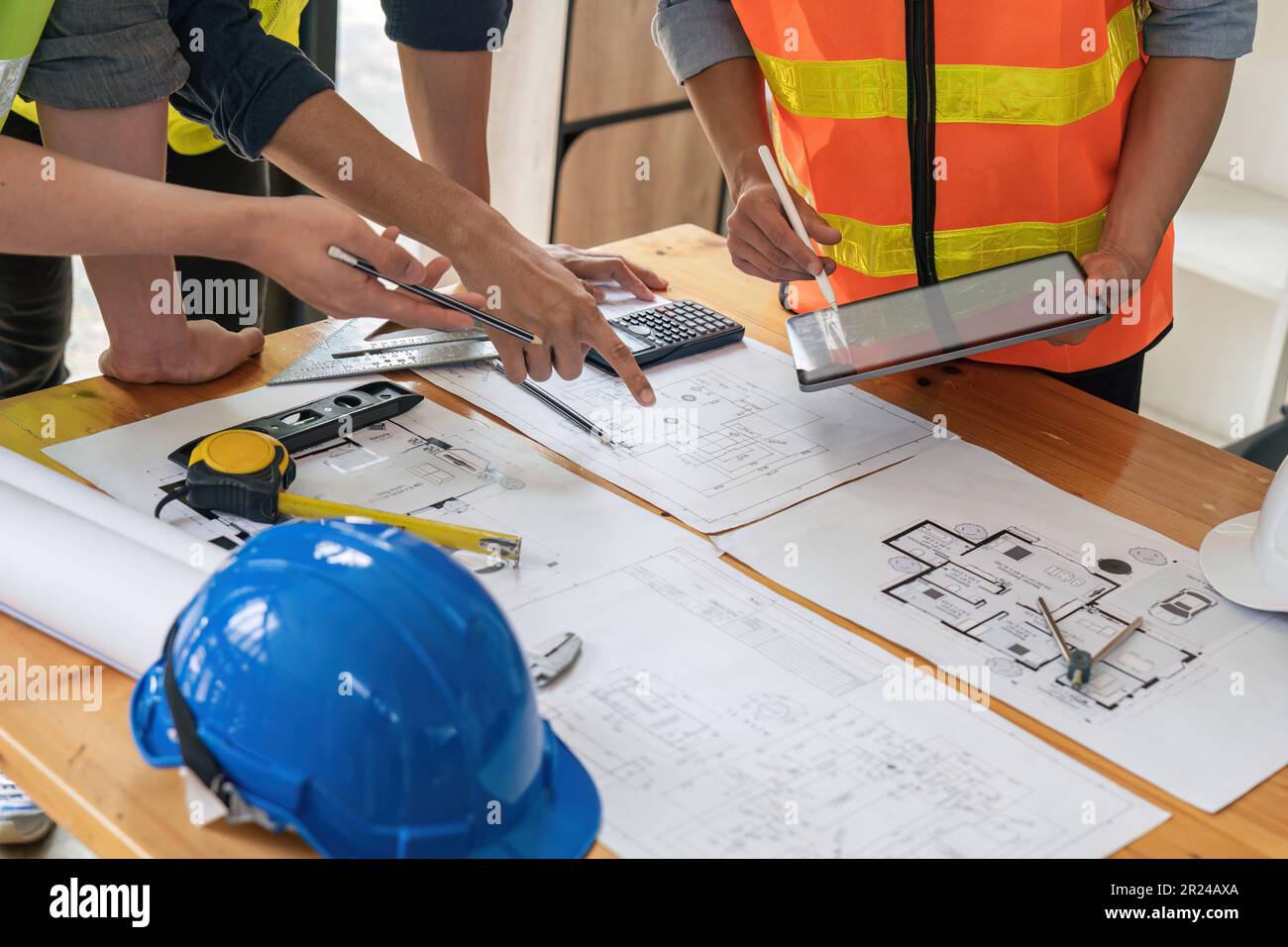 construction engineers team using blueprint and tablet of project plan ...