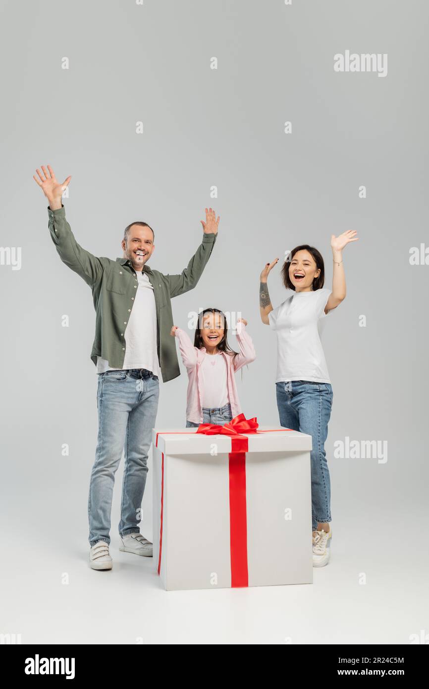 Excited parents in casual clothes waving hands at camera near preteen ...