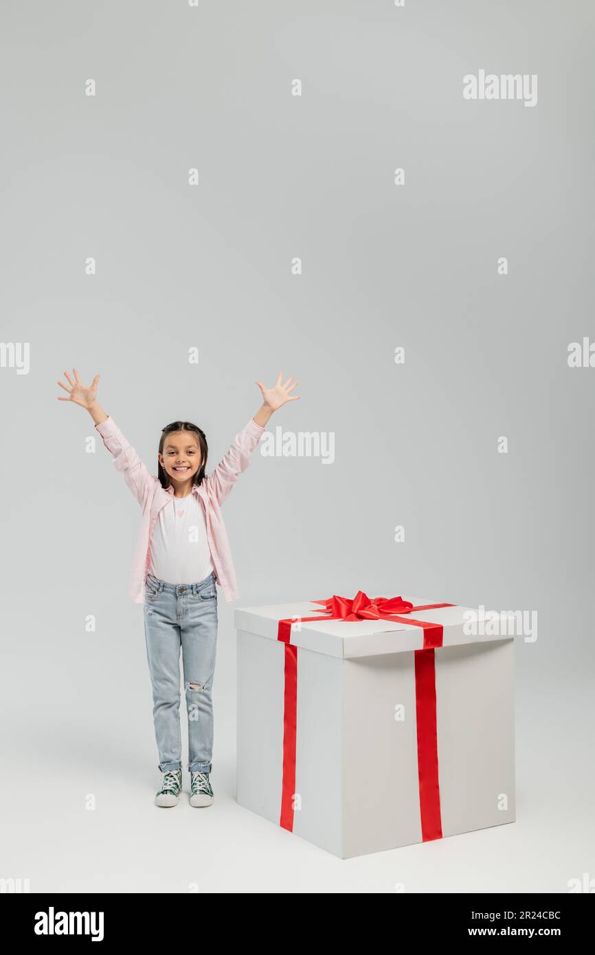 Carefree preteen girl in casual clothes waving hands at camera while ...