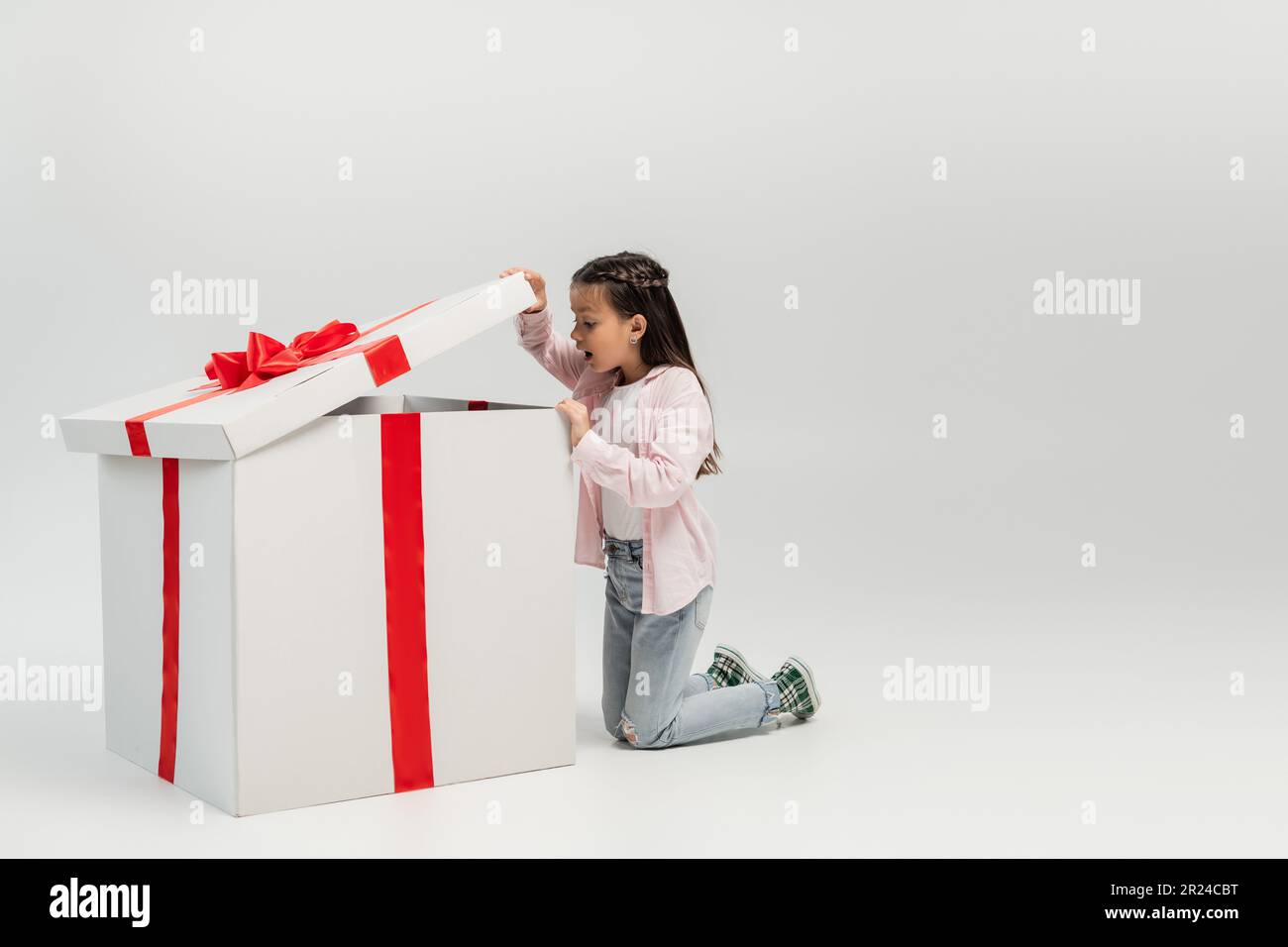 Side view of shocked preteen kid in casual clothes opening and looking ...