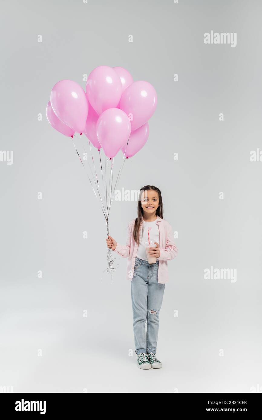 Full length of smiling preteen girl in casual clothes holding pink ...
