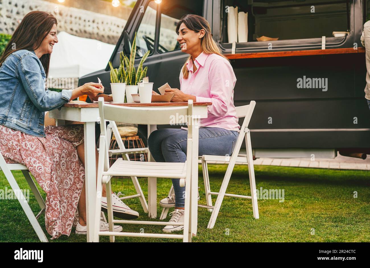 Happy people having fun eating and drinking outdoor at food truck ...
