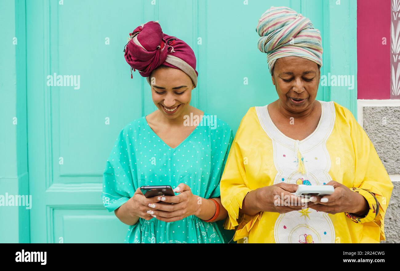 Happy african mother and her daughter wearing afro clothes using mobile ...