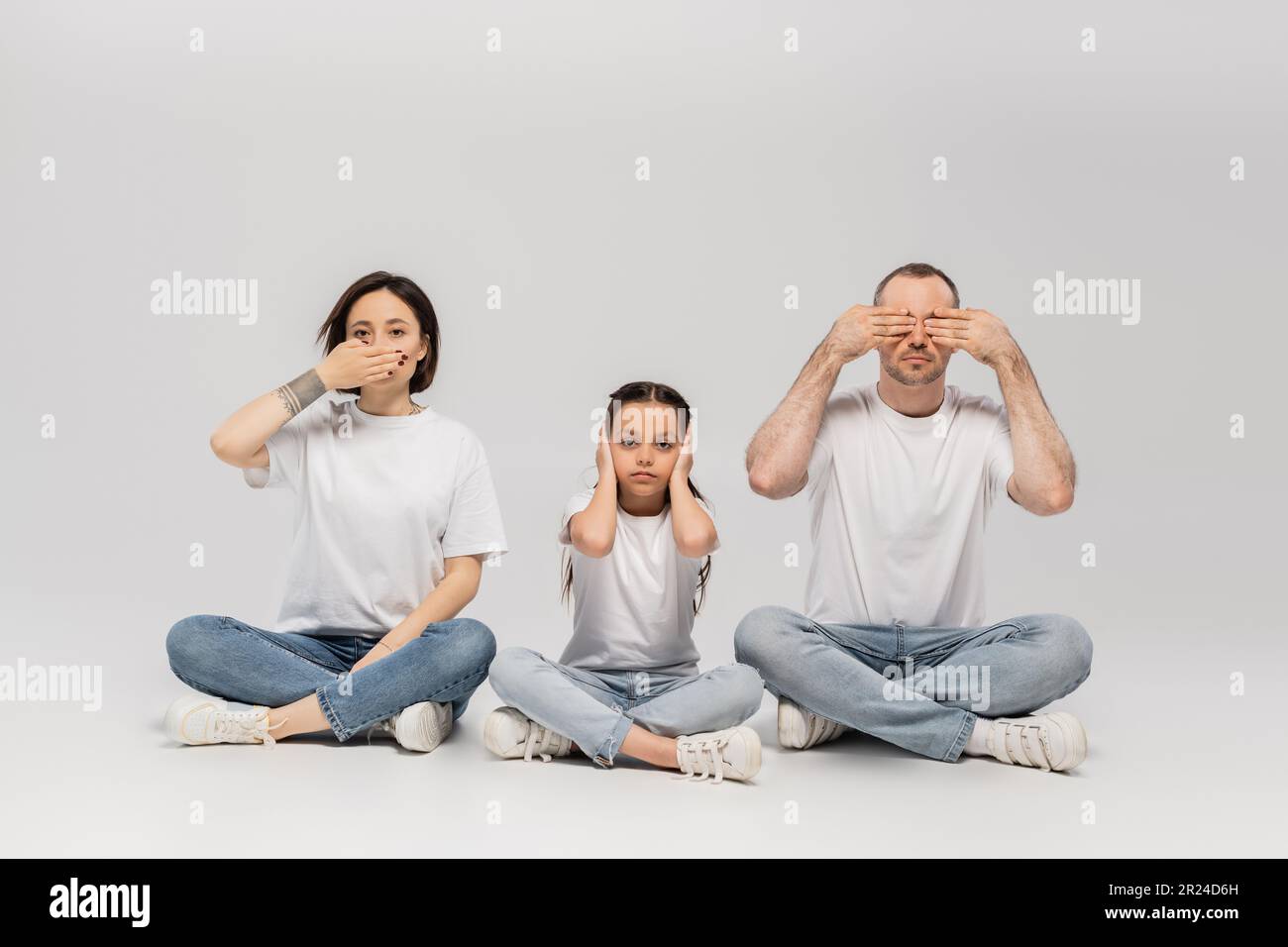 Family sitting with crossed legs in white t-shirts and blue denim jeans ...