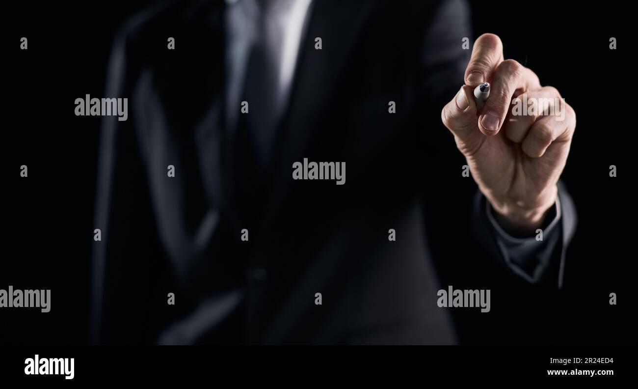 Left hand writing with marker on transparent board on black background ...