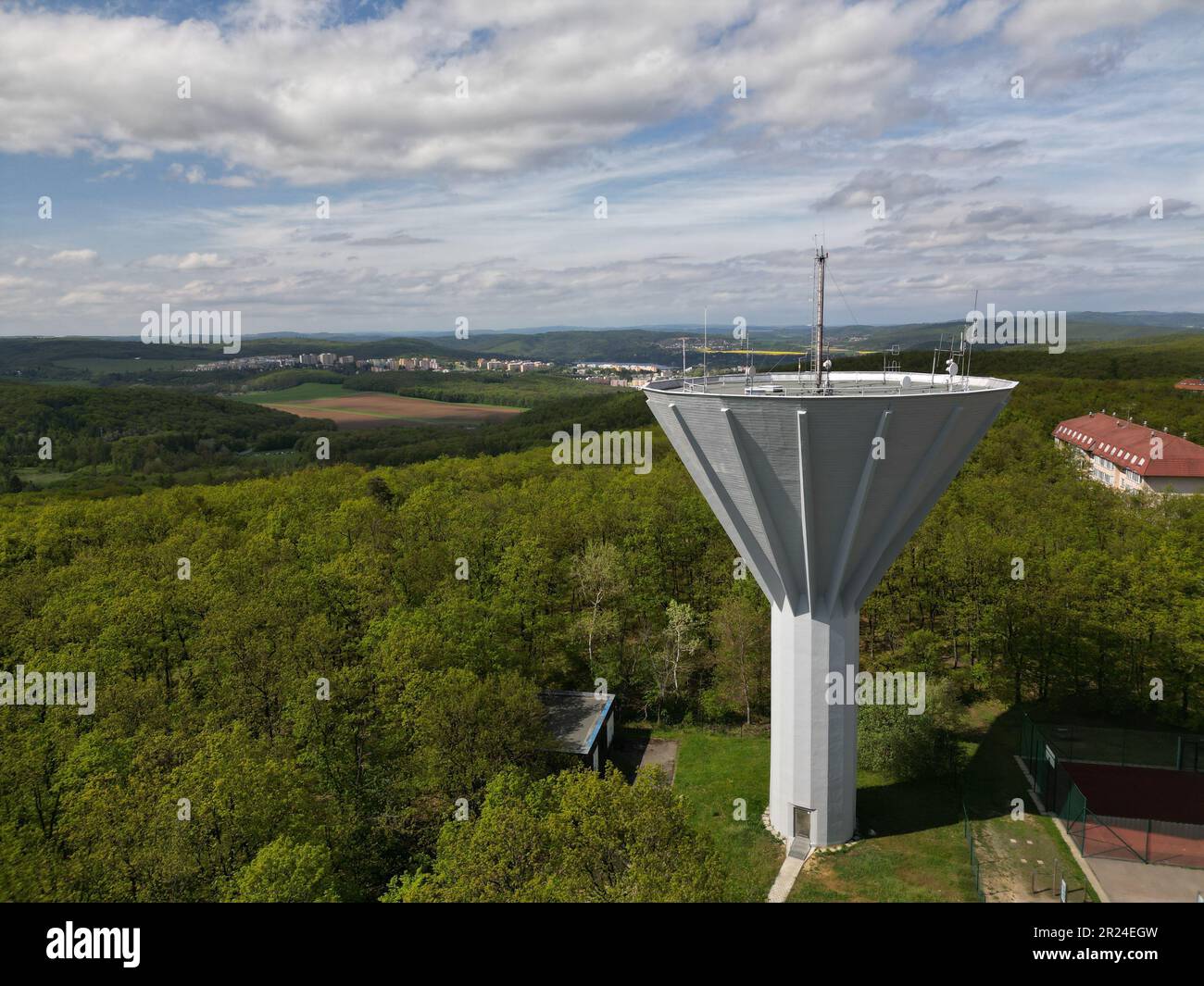 An aerial view of a cylindrical water tower surrounded by a lush green ...