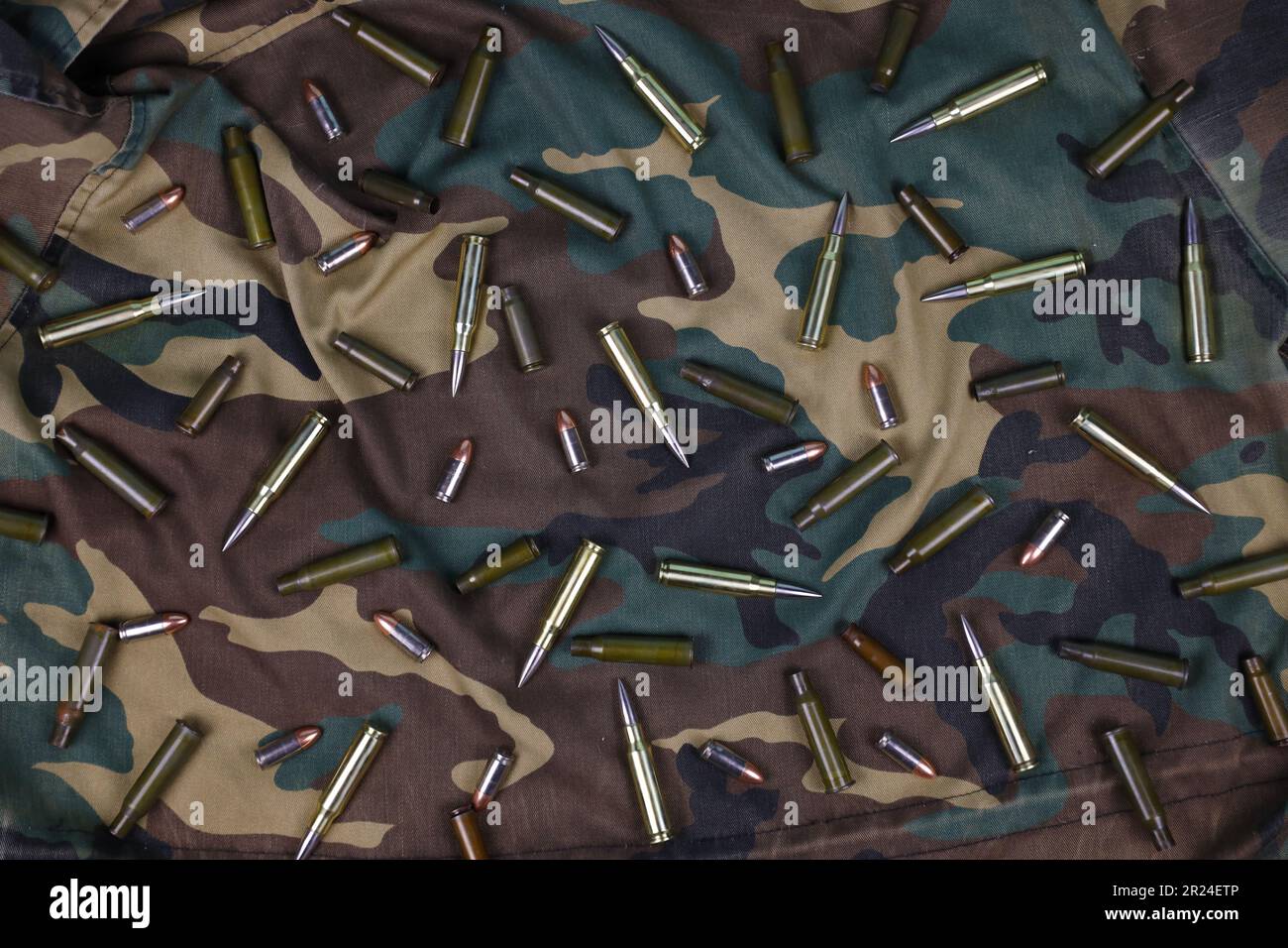 Many rifle bullets and cartridges on dark camouflage background ...