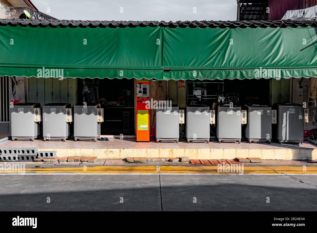 Laundry service with a row of washing machines set on the pavement in ...
