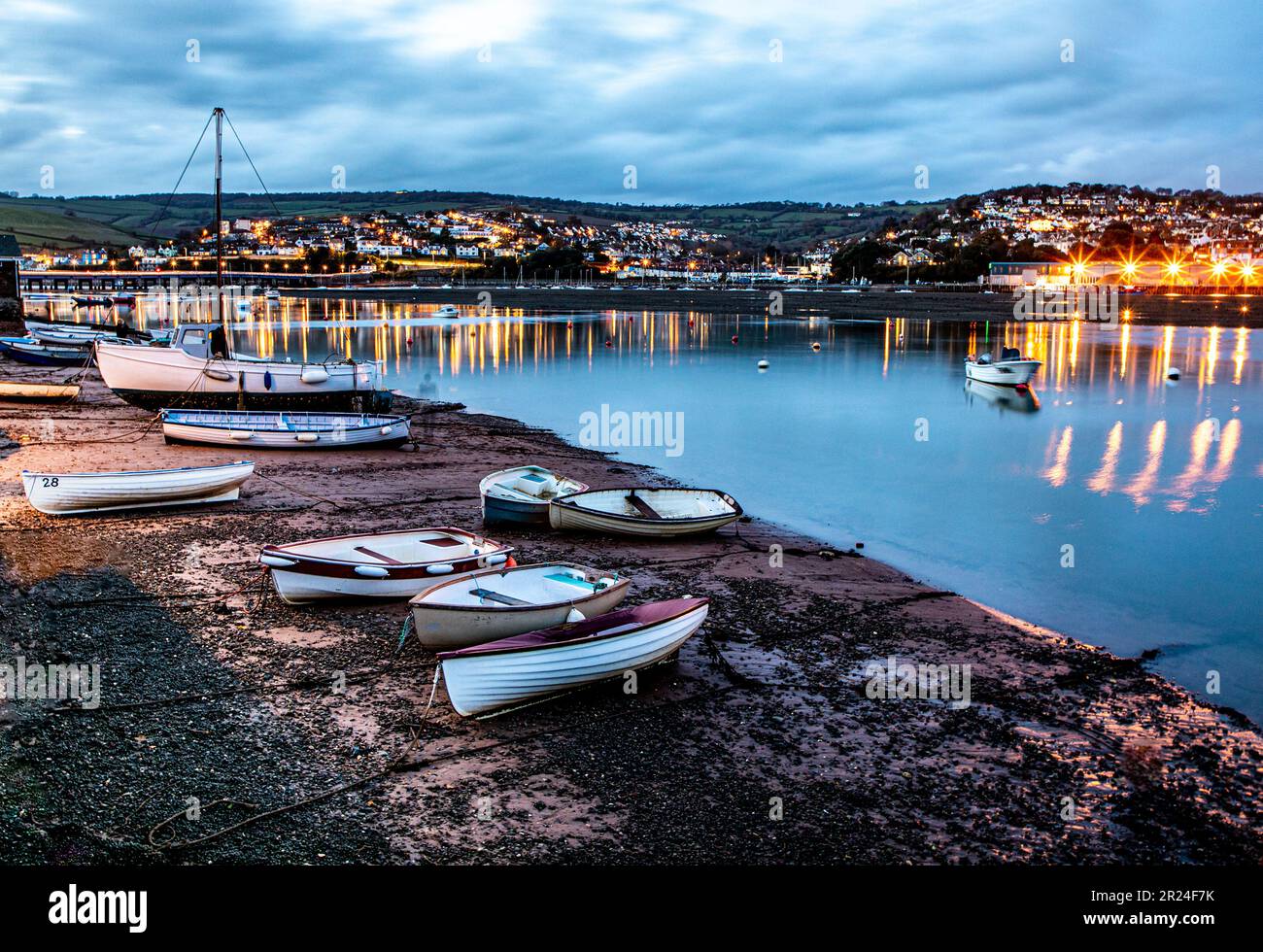 Rowing gigs moored in twighlight at low tide on Shaldon beach in Devon ...