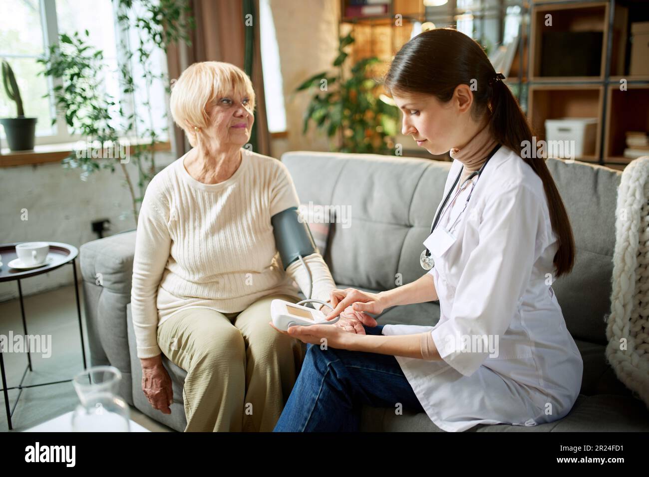 Female doctor measuring pressure of senior woman, patient with modern ...