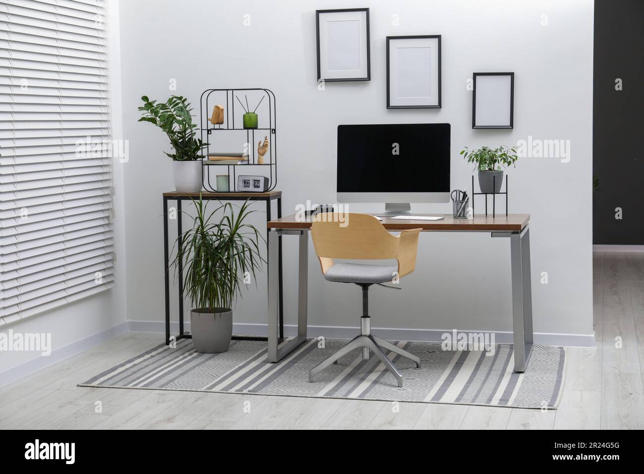Cozy workspace with computer on desk, chair and houseplants near white ...