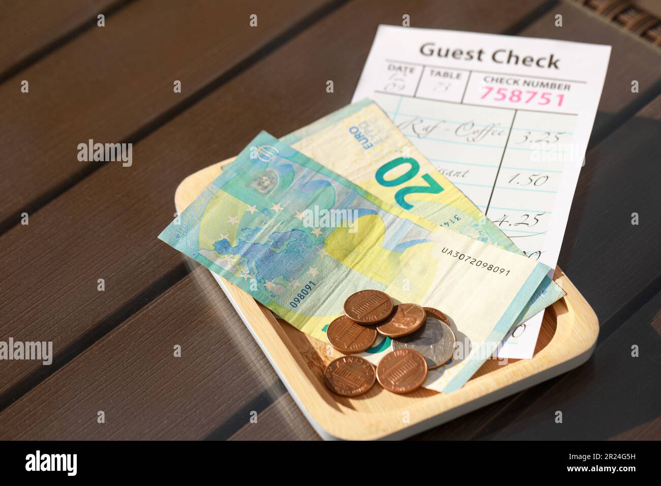 Wooden plate with payment for order and receipt on table, closeup ...