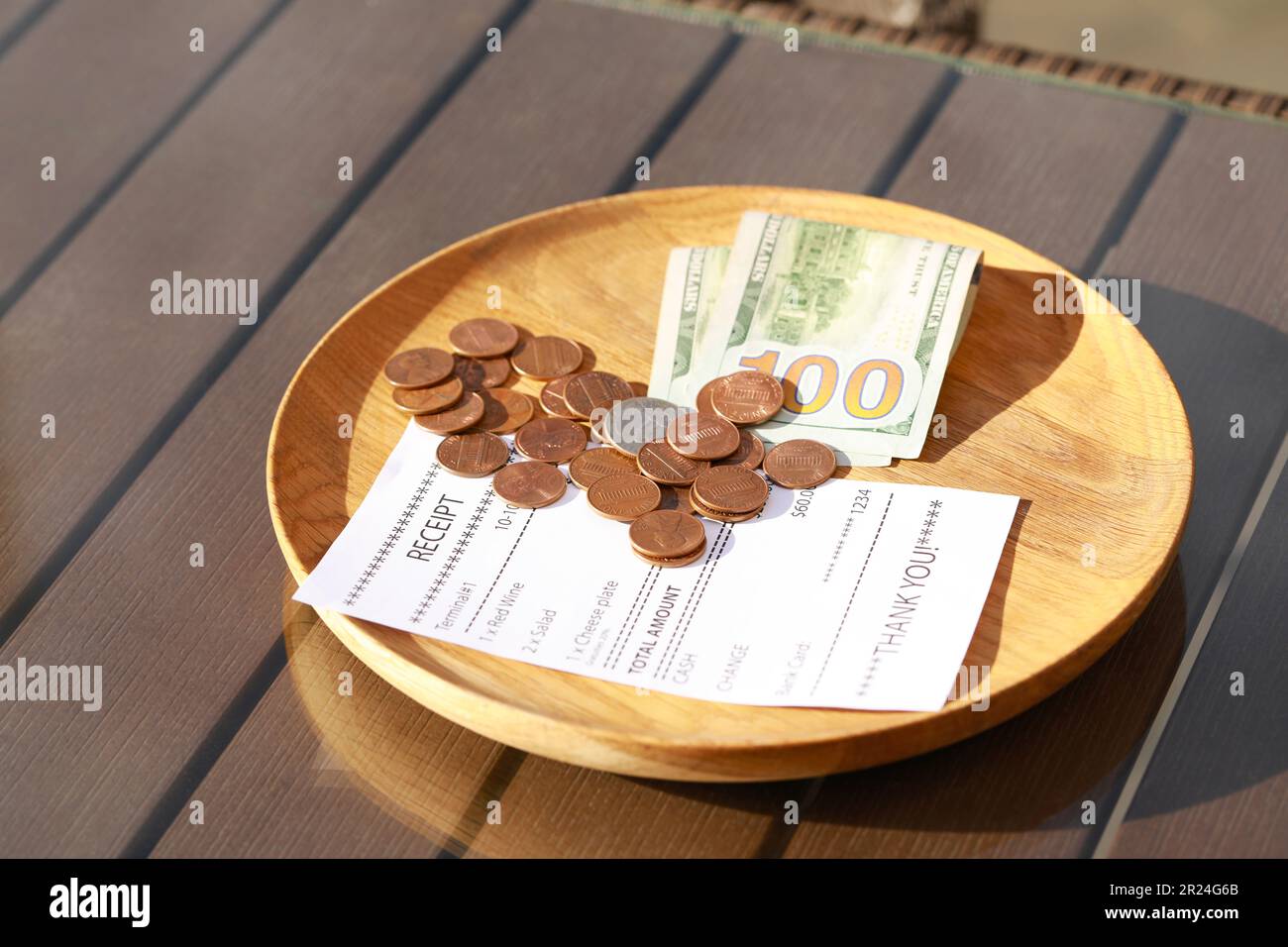 Wooden plate with payment for order and receipt on table, closeup ...