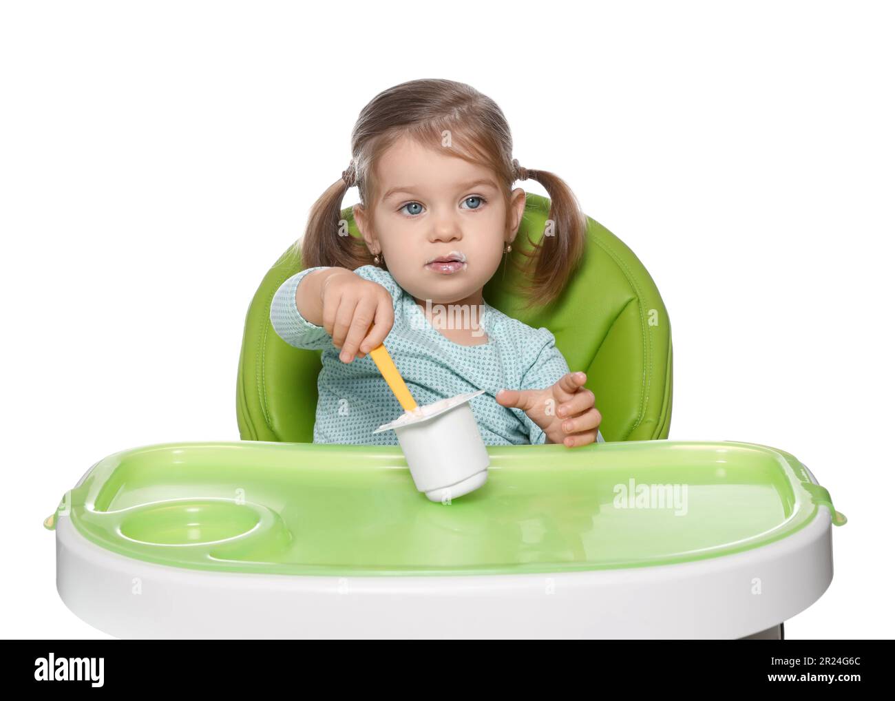 Cute little child eating tasty yogurt from plastic cup with spoon in ...