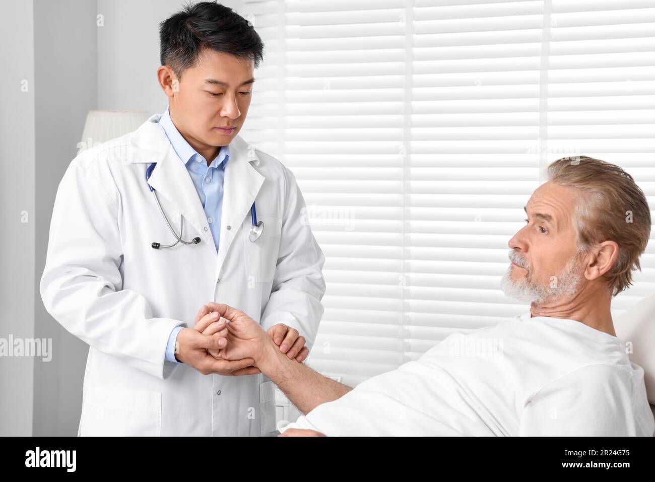 Doctor checking senior man`s pulse in hospital Stock Photo - Alamy