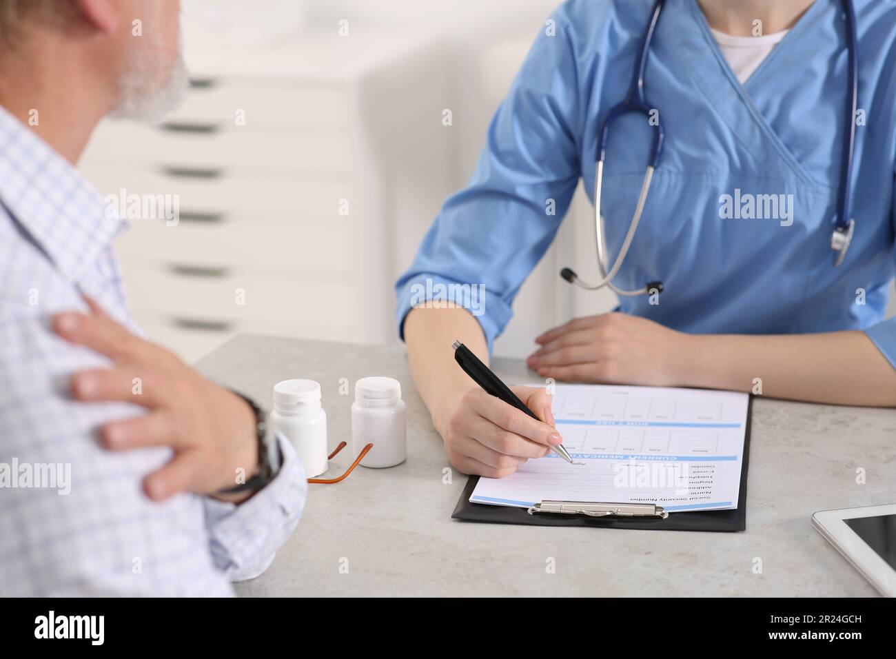 Doctor filling patient's medical card at table in clinic, closeup Stock ...