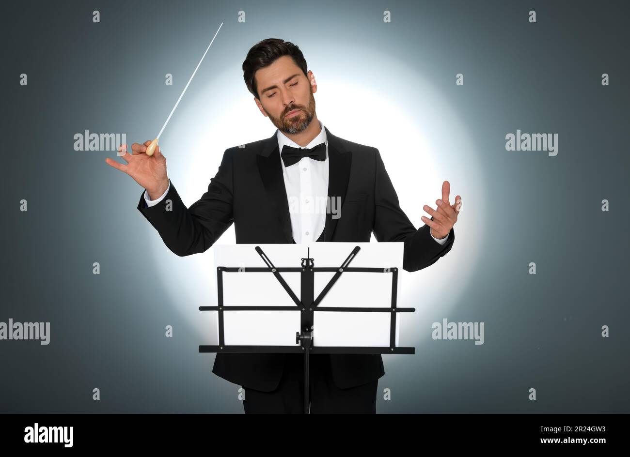 Professional conductor with baton and note stand on grey background ...