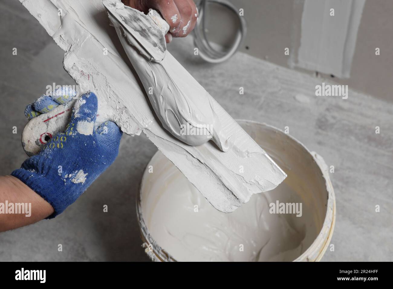 Professional worker putting plaster on putty knife indoors, closeup ...