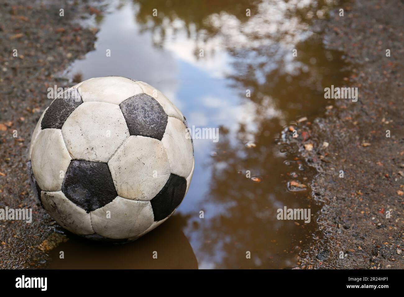 Dirty soccer ball in muddy puddle, space for text Stock Photo - Alamy