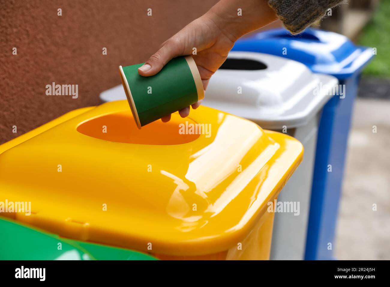 Woman throwing coffee cup into recycling bin outdoors, closeup Stock ...