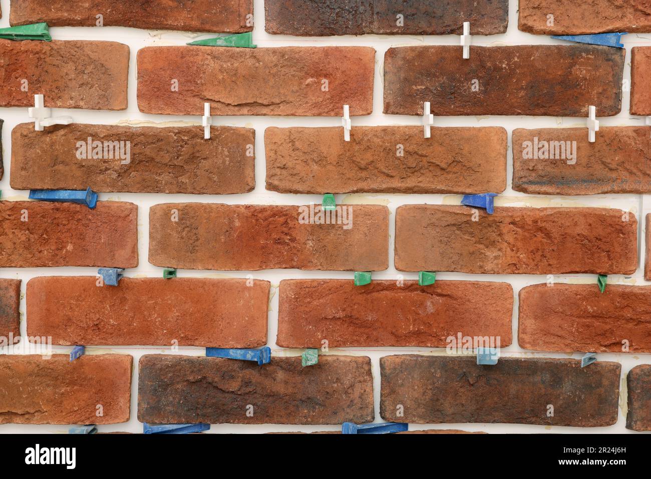 Decorative bricks with tile leveling system on wall Stock Photo - Alamy