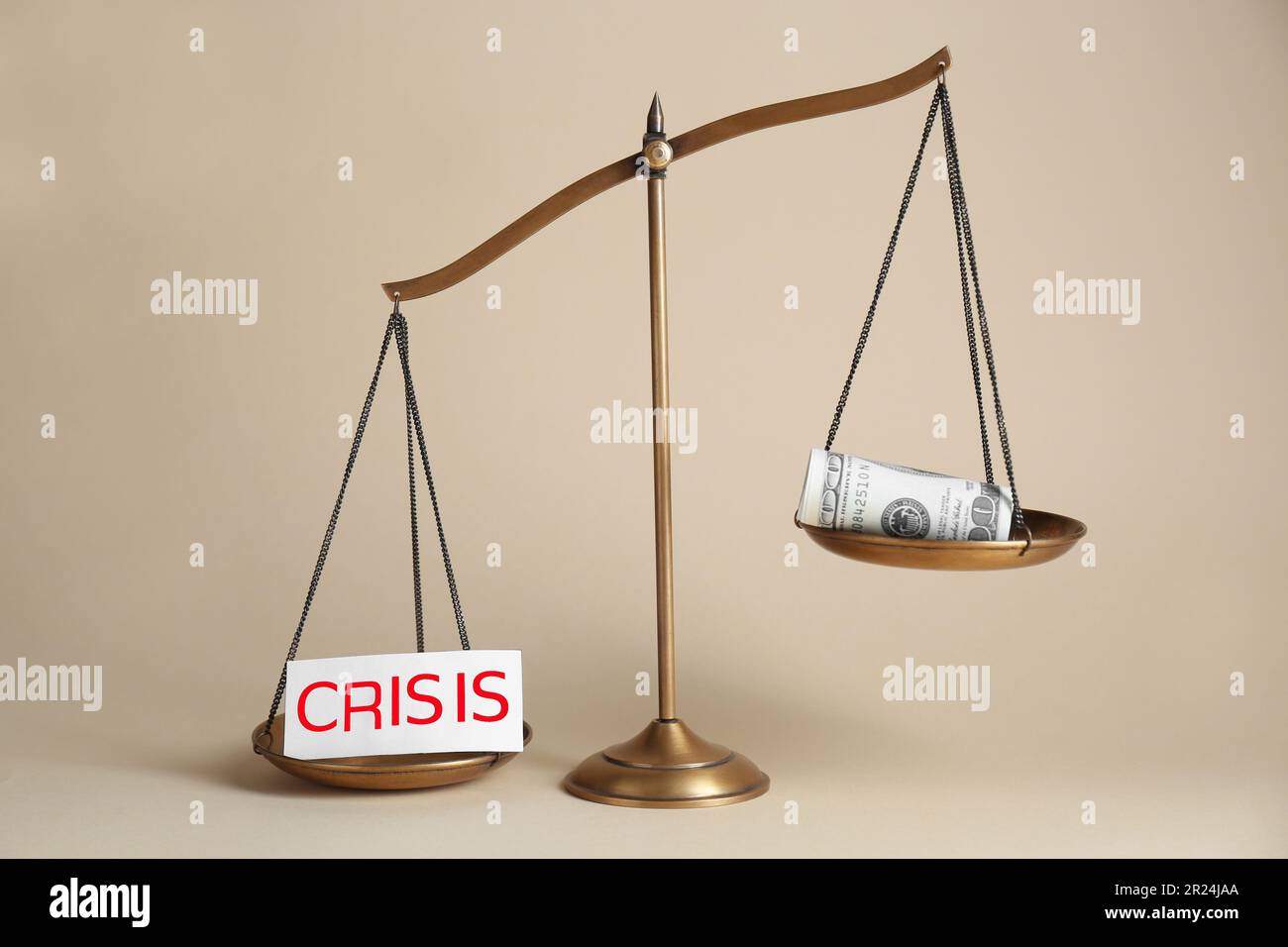 Scale with word Crisis and money on beige background Stock Photo - Alamy