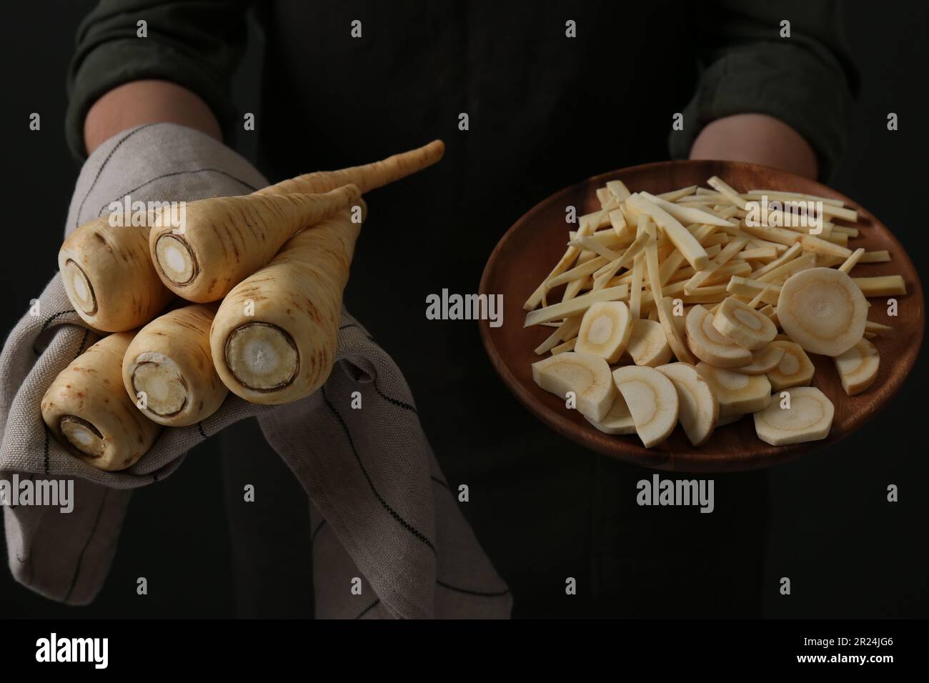 Woman holding whole and cut parsnips on black background, closeup Stock ...