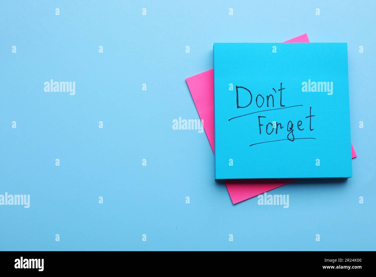 Paper note with phrase Don't Forget on light blue background, top view ...