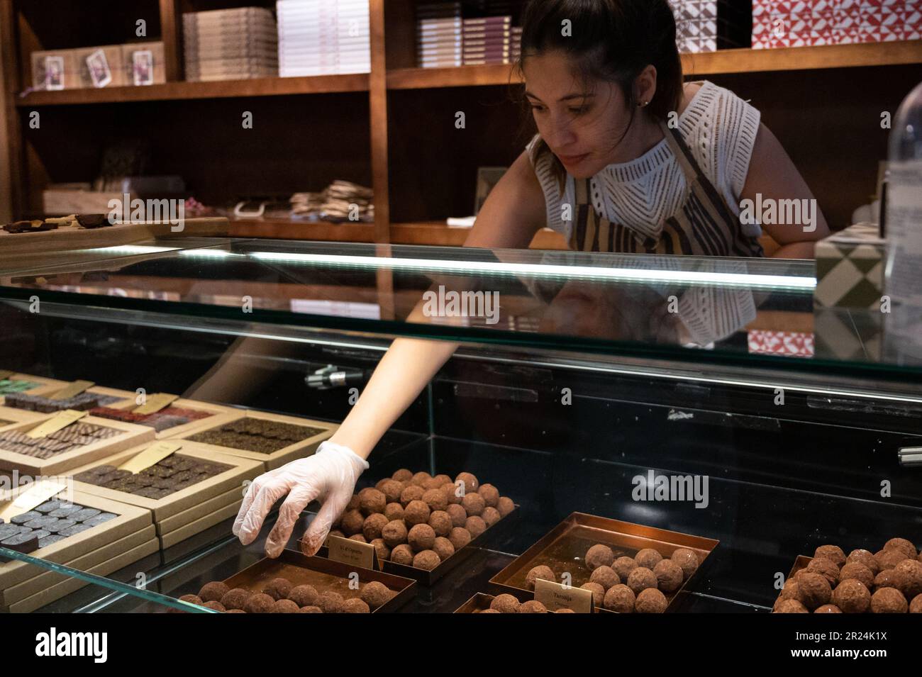 Detail of a young and pretty shop assistant in a chocolate shop serving ...