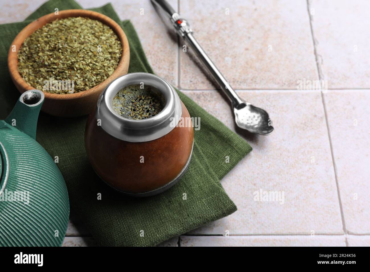 Calabash, bombilla, bowl of mate tea leaves and teapot on tiled table ...