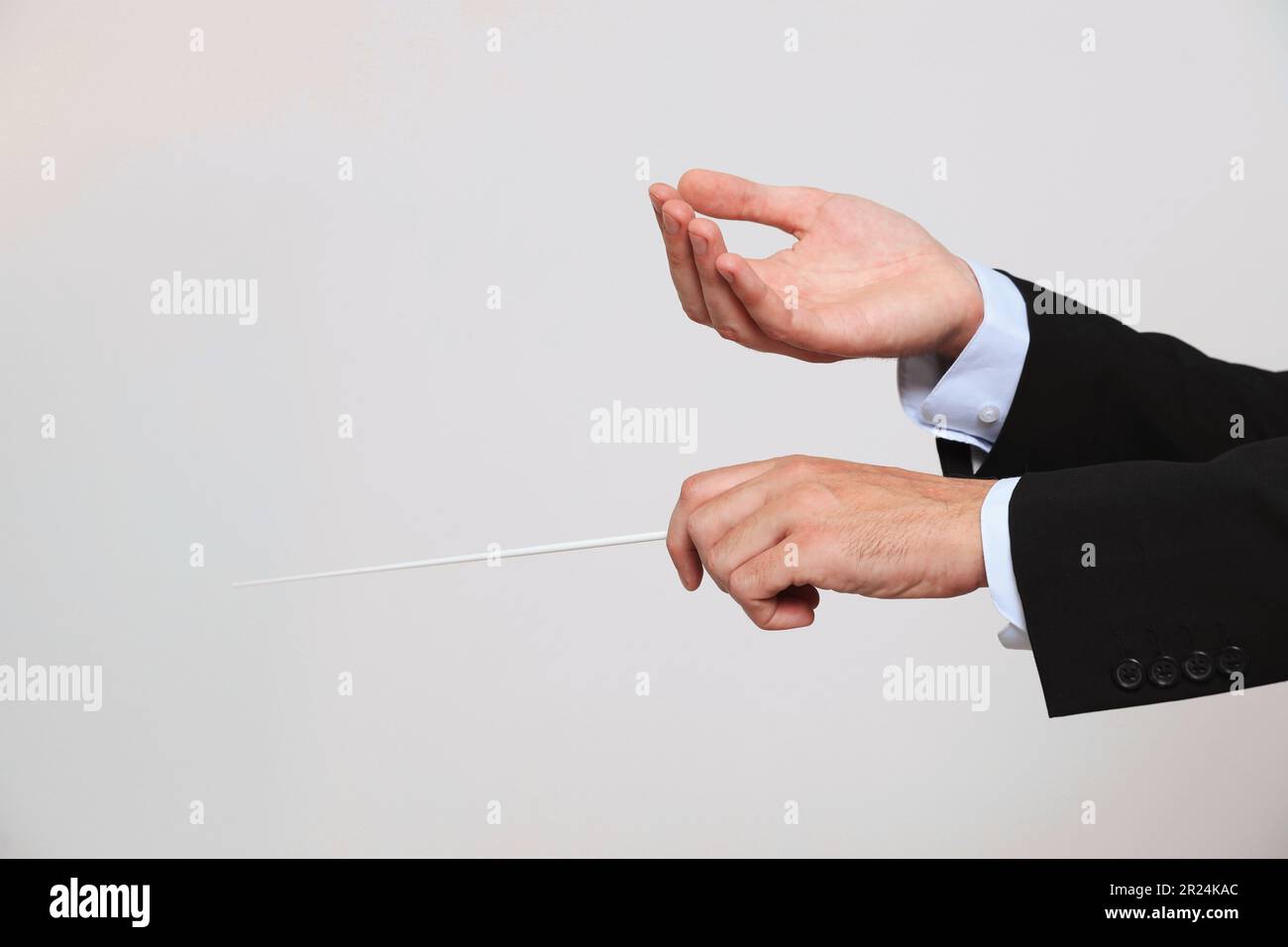 Professional conductor with baton on light grey background, closeup ...