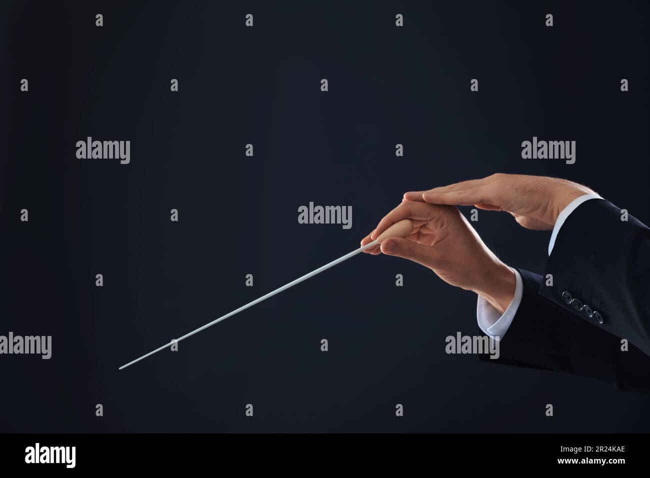 Professional conductor with baton on black background, closeup. Space ...