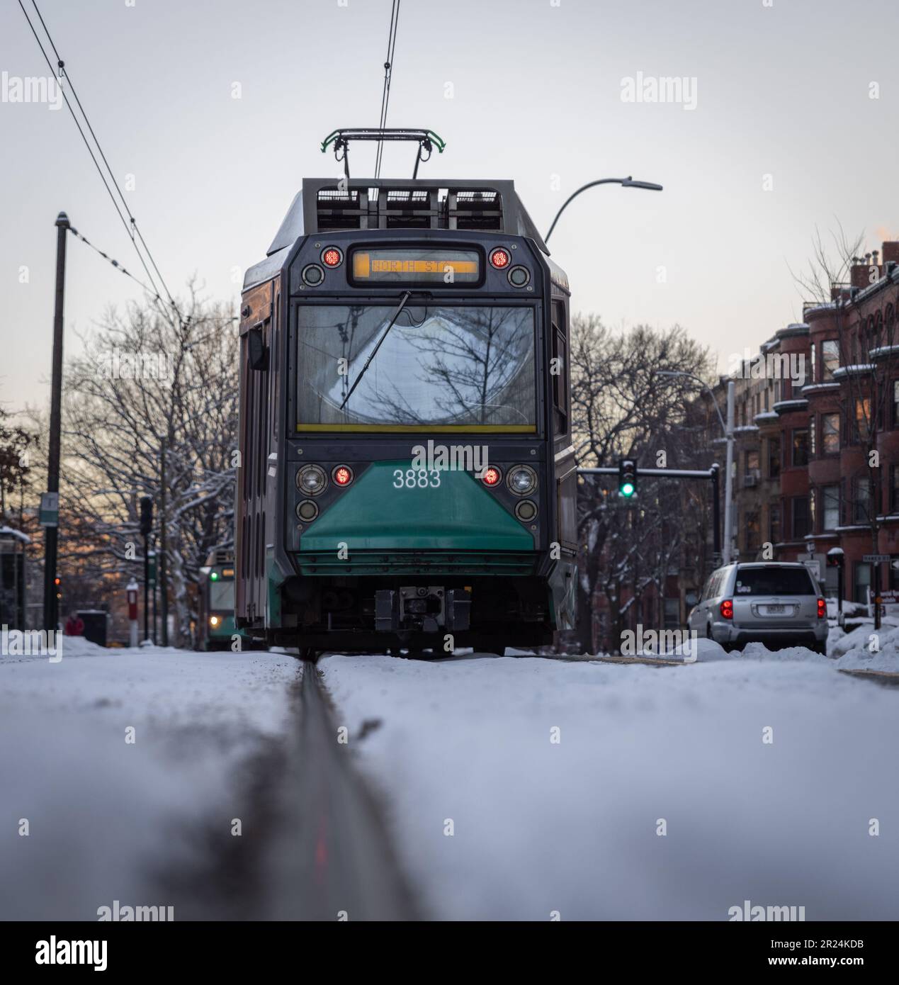 A vintage-style green tram driving down a set of tracks in a blizzard ...