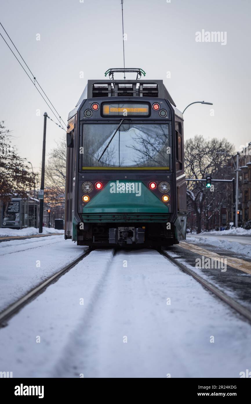 A vintage-style green tram driving down a set of tracks in a blizzard ...