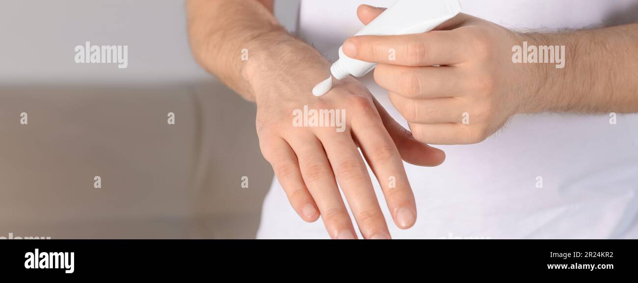 Man applying cream onto hand at home, closeup. Banner design Stock ...