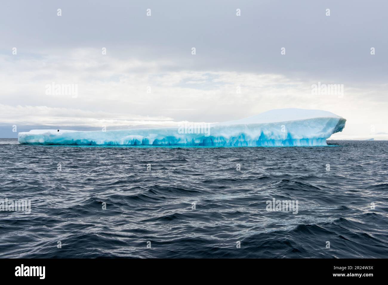 Brown Bluff, Antarctica. An iceberg juts out of the sea in the ...