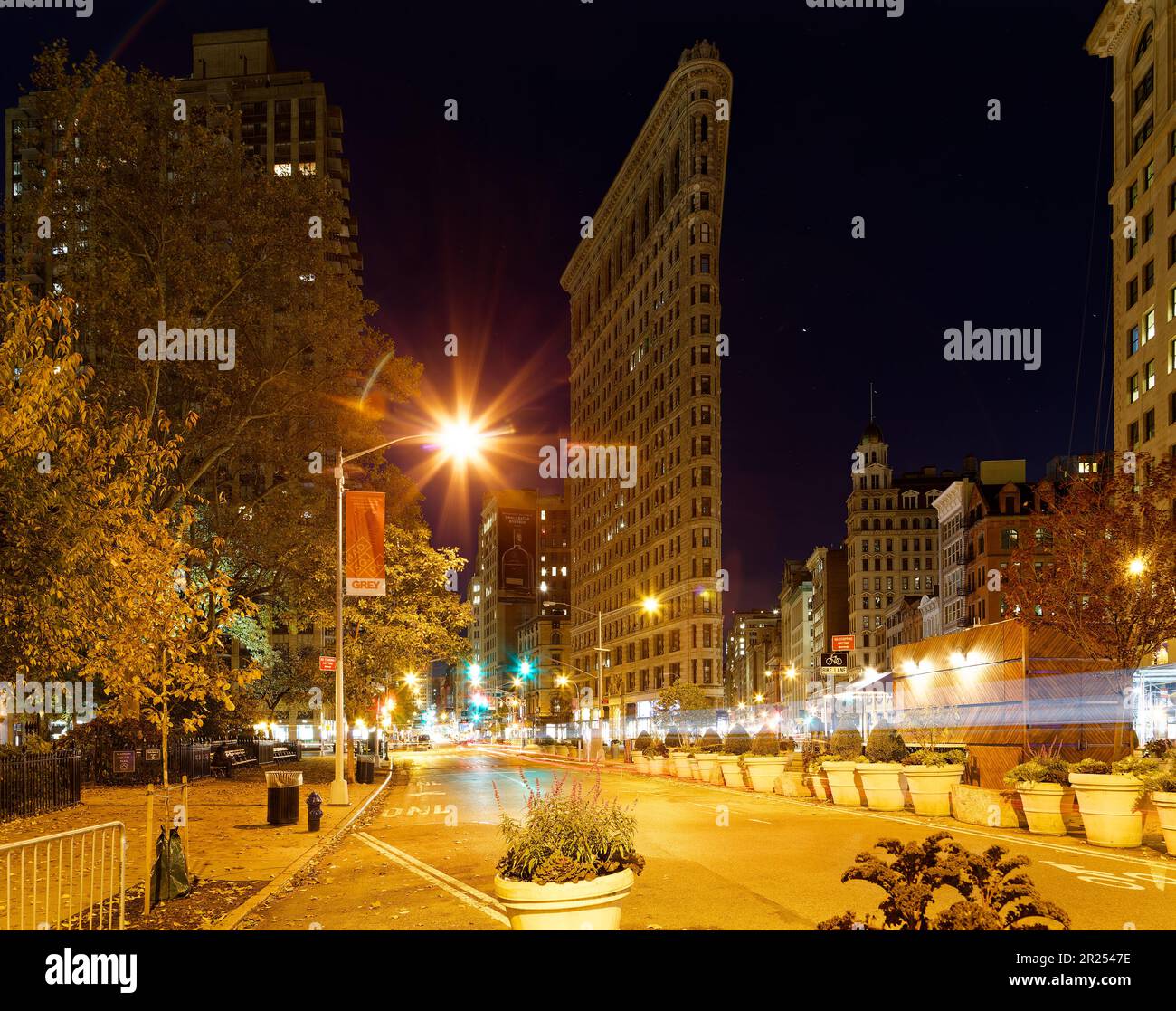 The Flatiron Building glows warm under streetlights under an indigo pre ...